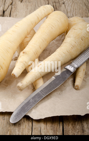fresh parsnip lie with a knife on brown paper Stock Photo - Alamy