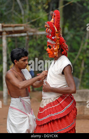 Painting the face of a Theyyam performer, preparing for a ritual, near ...