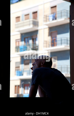 Smoking man in a window opening. Man with a pipe and a drinking cup in ...