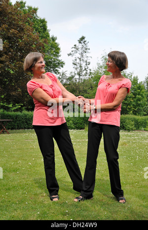 Photo of two friendly relaxed sisters wear jeans shirts smiling sitting ...
