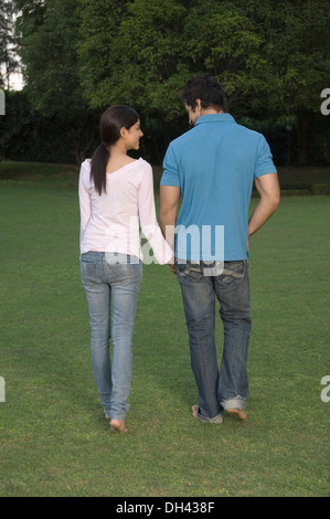 Rear view loving couple walking holding hands outdoors Stock Photo - Alamy