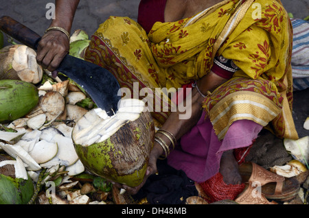 Lady vendor cutting coconut with sickle on road side at Kolkata India ...