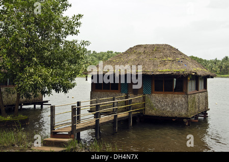 Thatched Huts built on stilts over water in front of with green ...