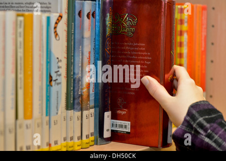 Close up of hand, pulling book off shelf in library Stock Photo - Alamy