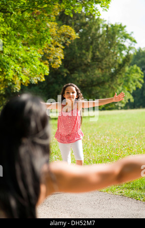 Girl spreading arms and running towards a young woman isolated on white ...