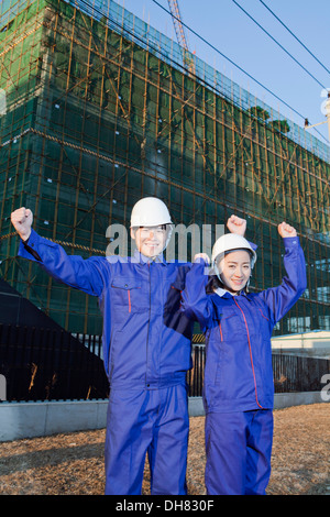 Happy construction engineers cheering at site Stock Photo - Alamy