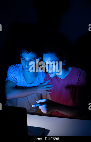 Two guys in front of a computer screen getting all excited about ...