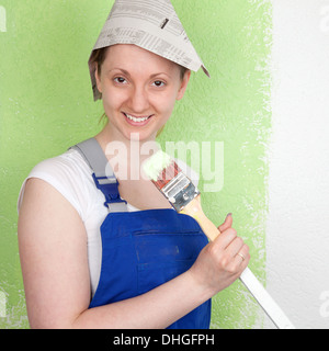 Woman painter holding paintbrush in hand and palette while smiling and ...