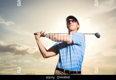 Golfer at sunset, Man swinging golf club with dramatic sunset sky Stock ...
