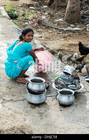 Indian woman washing dishes outside their rural indian village home ...
