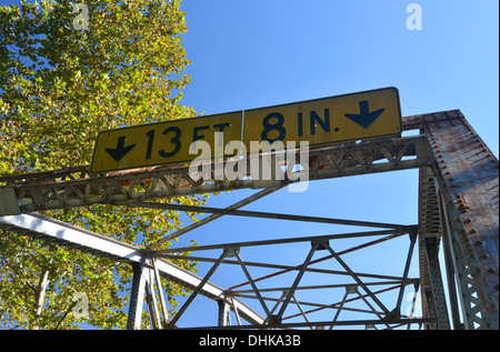 Height restriction sign on old truss girder box bridge crosses a river ...