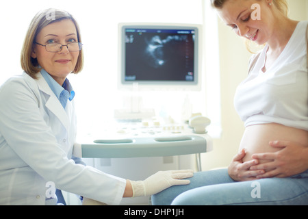 Pregnant woman smiling during a medical ultrasound examination showing ...