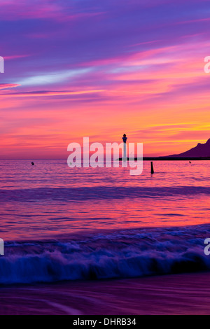 A vertical shot of a bright sunset over the lake and the silhouettes of ...
