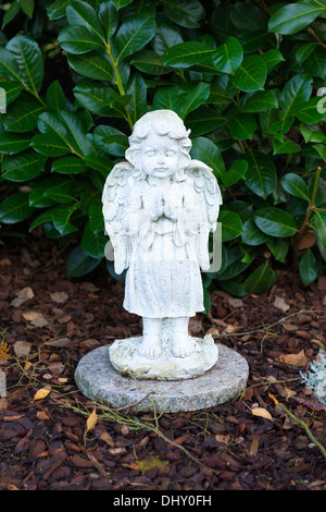 Small white praying angel statue sitting in its wings surrounded by ...