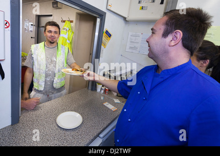 Construction workers getting food from onsite canteen through serving ...