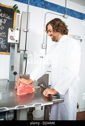 Portrait of smiling male butcher in white robe working with halal meat ...