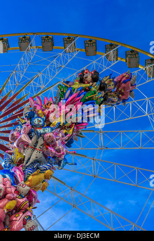 A photograph of a tower of balloons in front of a ferris wheel at the ...