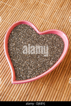 Heart-shaped bowl of chia seeds on chia background. Gluten free and ...