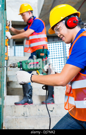 Asian Indonesian construction workers with helmet and safety vest on a ...