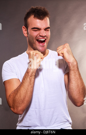 Young handsome unshaven man screaming and gesturing as winner isolated ...