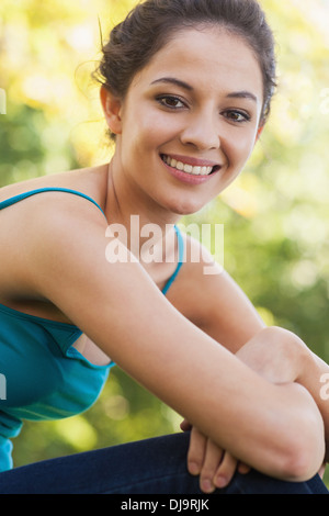 A side view of a brunette woman sitting on concrete stairs with shadow ...