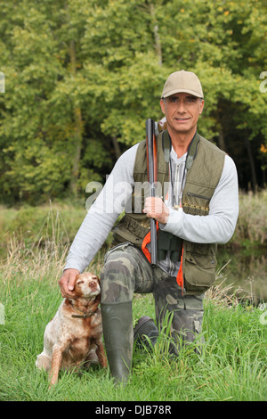 Hunter crouching by dog Stock Photo - Alamy