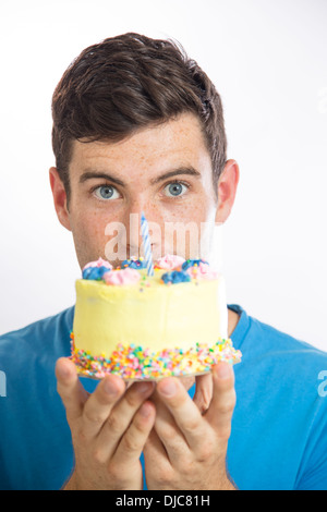 a man with a birthday cake in his hands and in a cap on a yellow ...