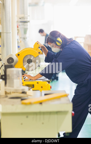 Concentrating trainee sawing piece of wood Stock Photo - Alamy