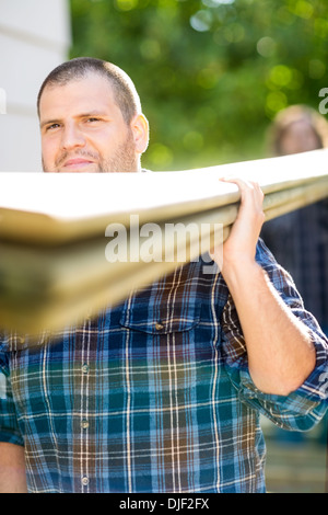 Man builder carrying wooden planks in construction site Stock Photo - Alamy