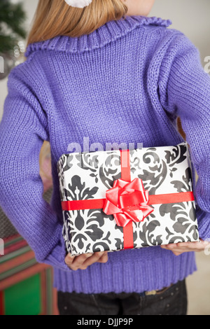 Girl Hiding Christmas Gift Behind Back Stock Photo - Alamy