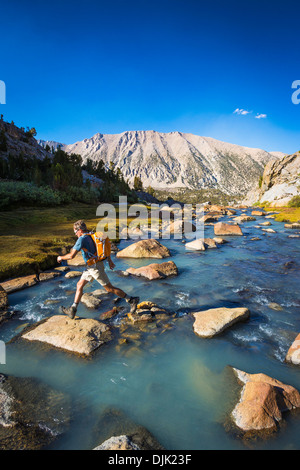 Hiker crossing stream in Sam Mack Meadow, John Muir Wilderness, Sierra ...