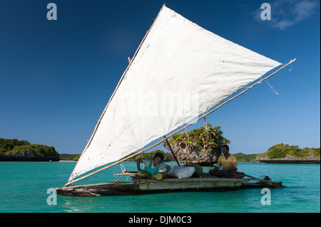 Man helming a traditional boat, a camakau, sailing across Fulaga lagoon ...