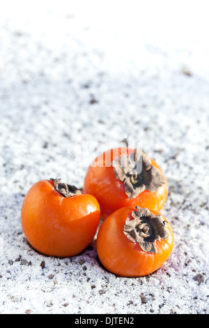 Three efresh orange persimmons on white snow, outside Stock Photo - Alamy