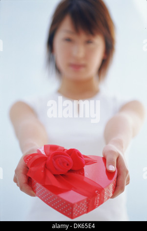 Hand offering box of heart shaped chocolates on pink background with ...
