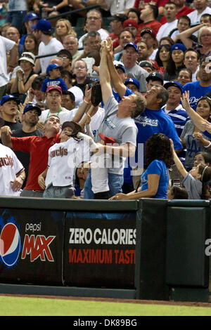 A fan grabs a foul ball during the ninth inning of a baseball game ...