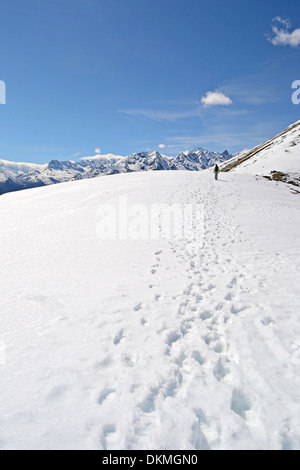 Alpinist hiking uphill on snowy slope in scenic high mountain landscape ...