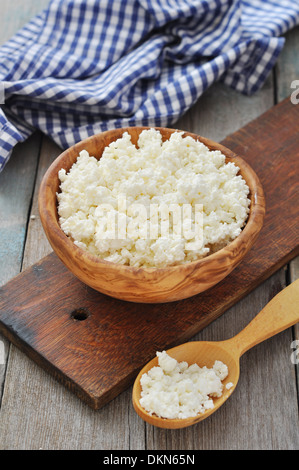 A white bowl of fresh cottage cheese on a rustic wooden table. This ...