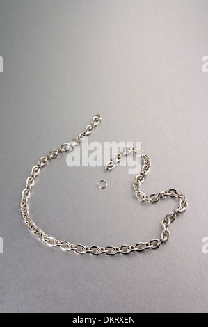 A silver link chain, broken with missing links on a silver background ...