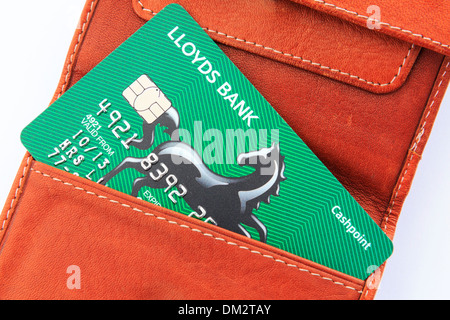 New Lloyds Bank cashpoint card in a blue purse isolated on a plain ...