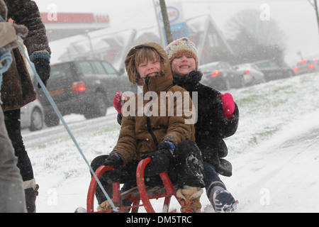 Two children pictured being pulled on a sledge in heavy snow in ...