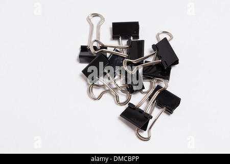 : A pile of black binder clips on a textured fabric surface, commonly ...