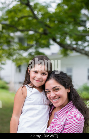 Hispanic mother and daughter wearing casual white t shirt over pink ...