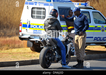 A South African JMPD police officer in riot gear holding police tape ...