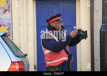 a parking warden or civil enforcement officer walking along a busy ...