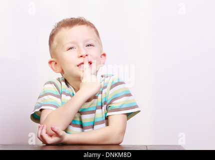 cute little boy asking to be quiet with finger on lips on blue ...