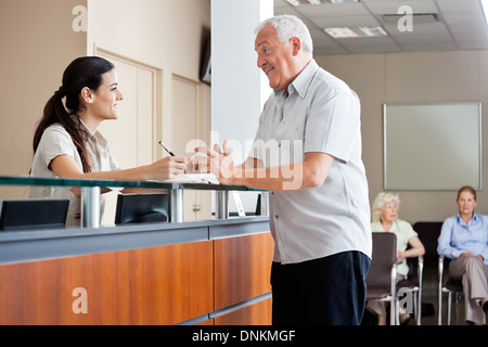 Friendly receptionist communicating with young female client Stock ...