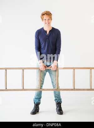 cheerful young handyman holding ladder Stock Photo - Alamy