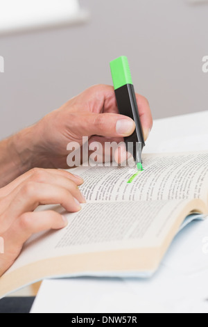 Hands holding a green highlighter and marking text in an open book ...