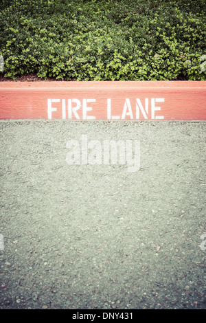 A red painted curb with a fire lane warning sign Stock Photo - Alamy