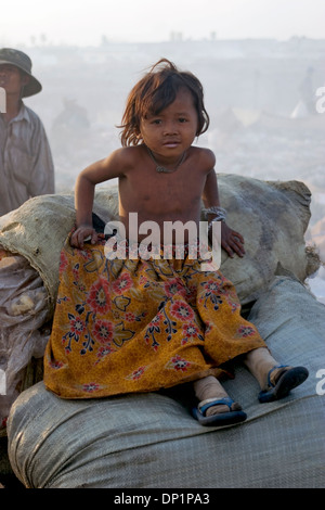 A child laborer girl who is a scavenger is sitting on a large sack at ...